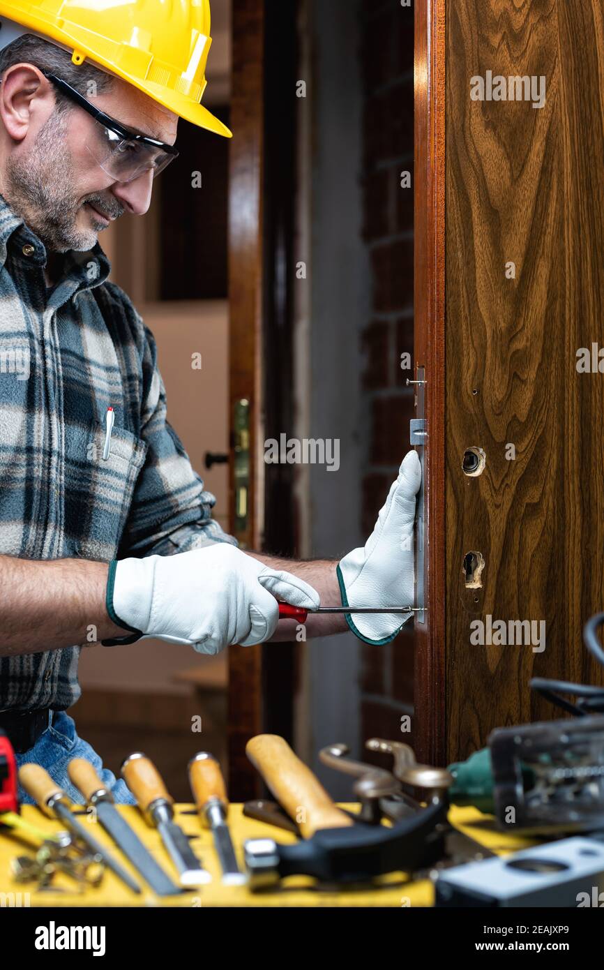 Carpenter at work repairs and installs the door lock. Carpentry Stock ...