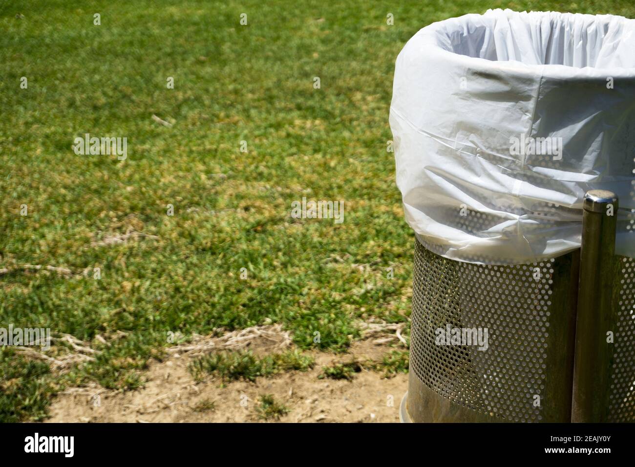 Trash bin in a park with white plastic bag. No people Stock Photo - Alamy