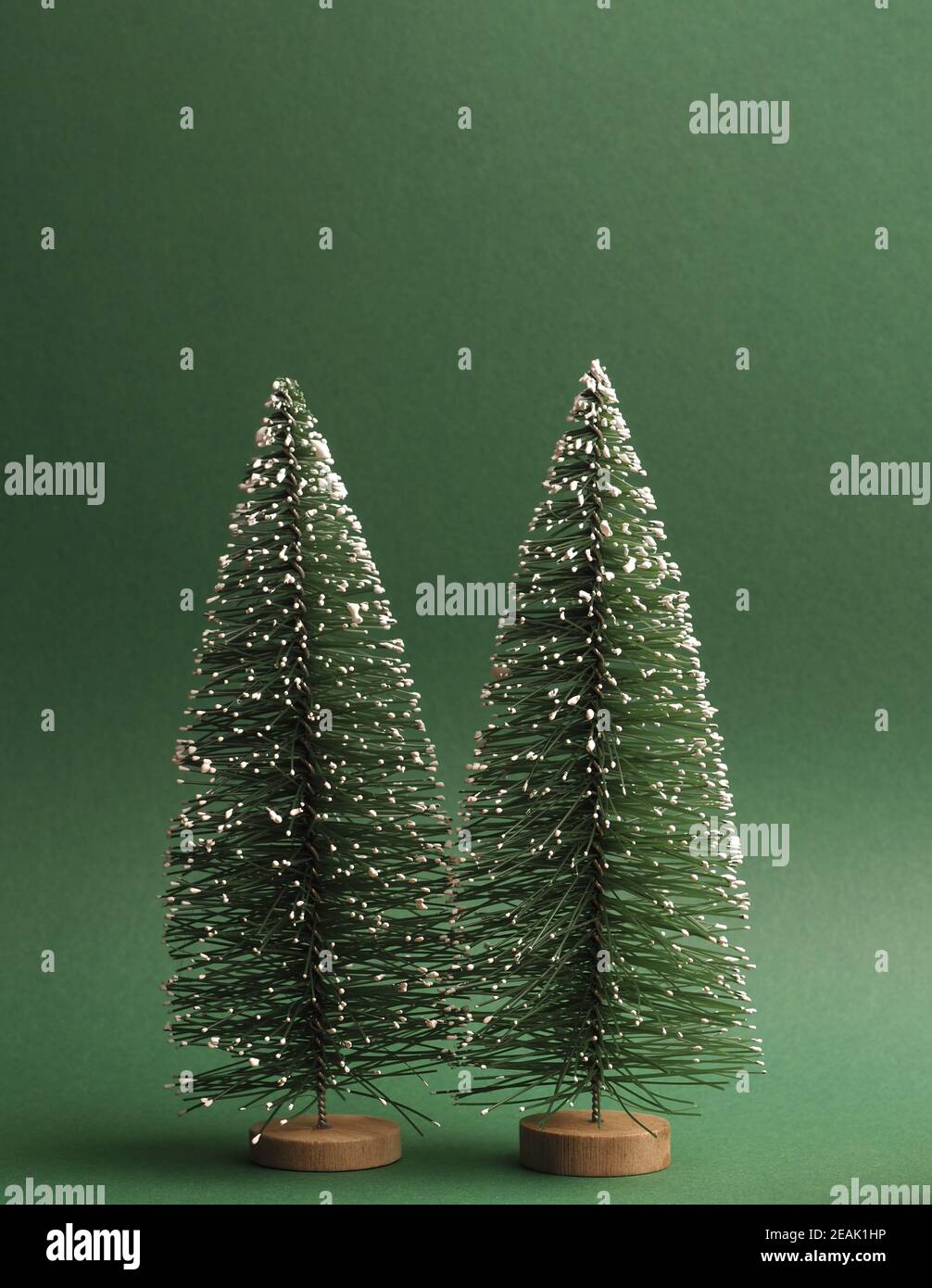 Two fir trees with snow on a green paper background, space for text on ...
