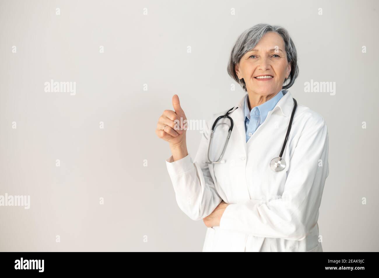 Positive senior mature female doctor with a stethoscope in a medical ...