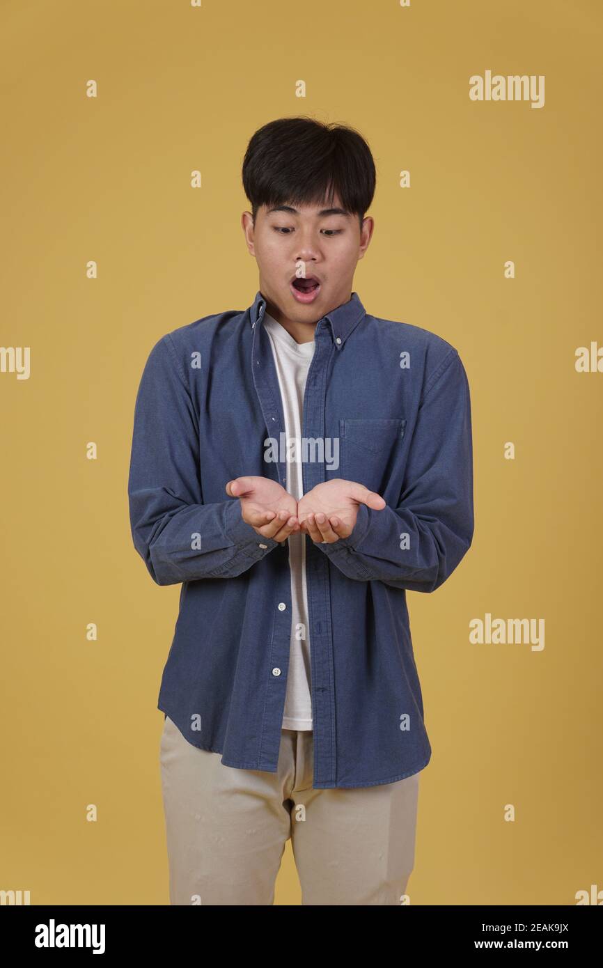 portrait of surprised excited young asian man dressed casually holding ...