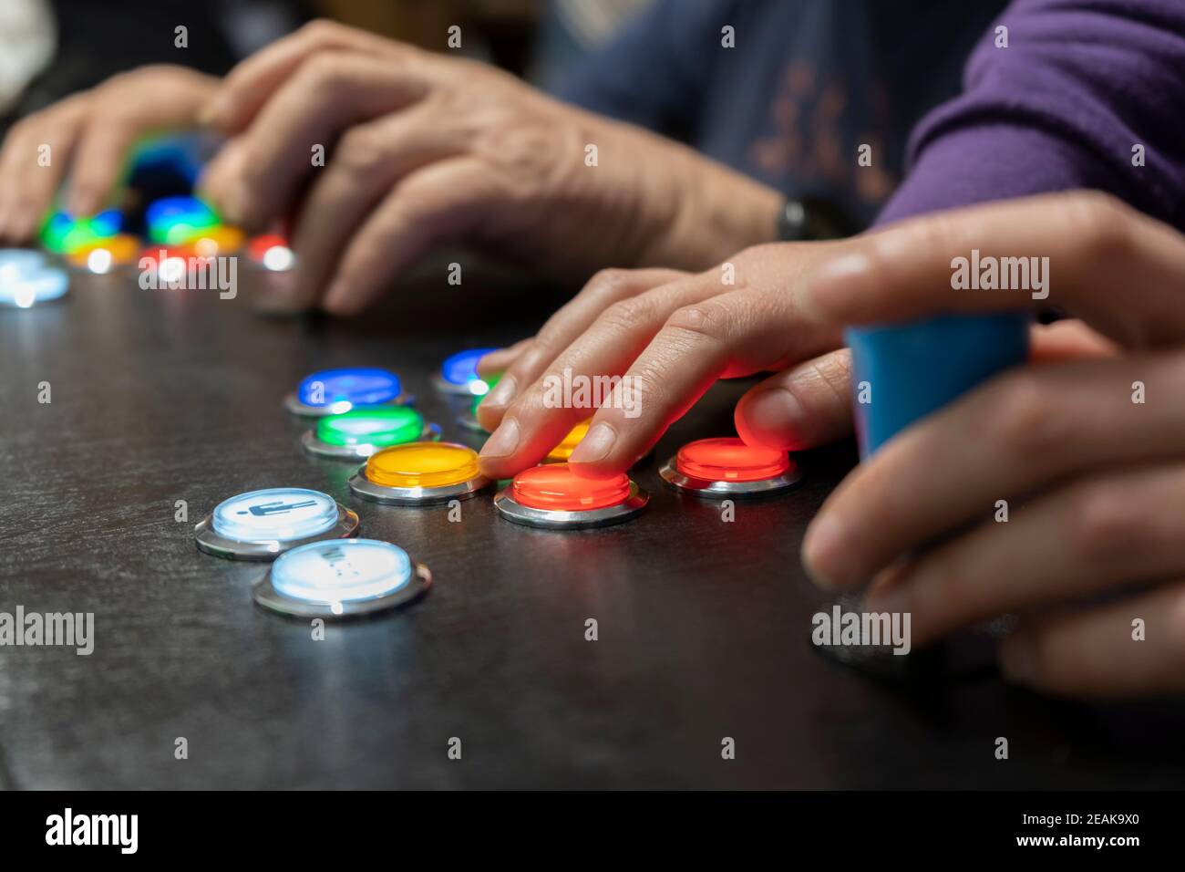 Closeup view of two people hands playing arcade vintage video games ...