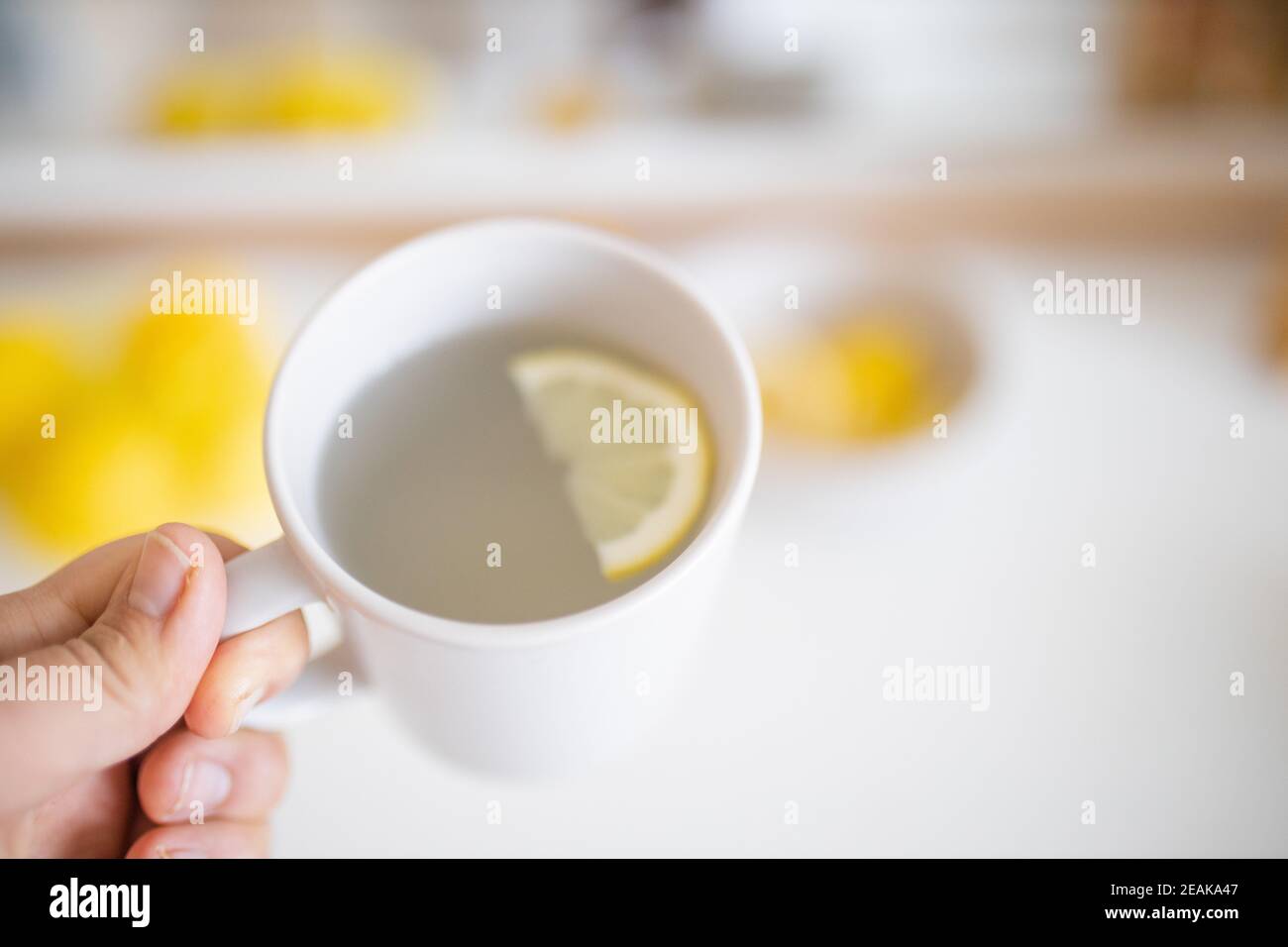 Hand holding a cup of lemon tea with a lemon slice inside Stock Photo ...