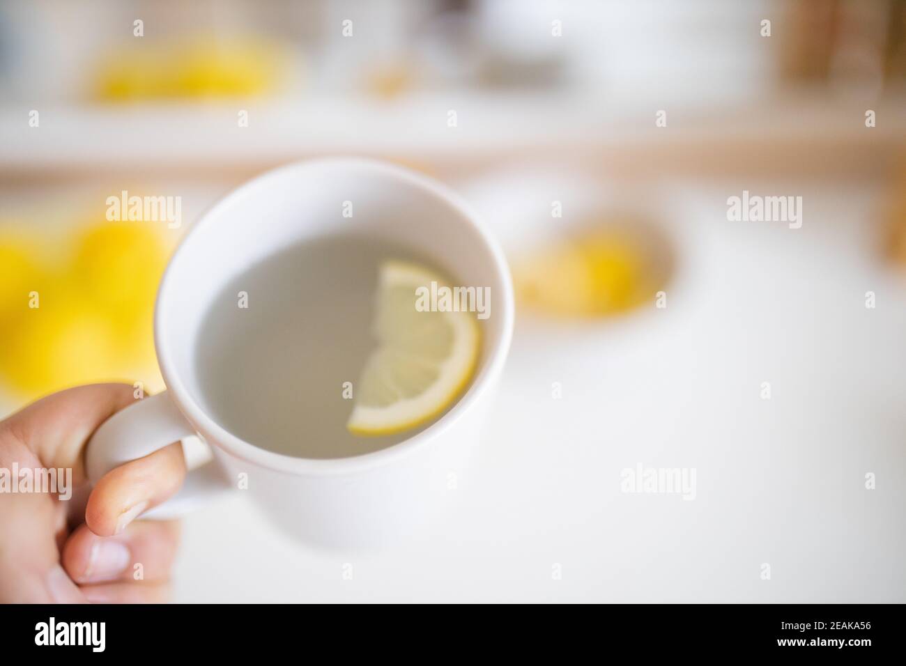 Hand holding a cup of lemon tea with a lemon slice inside Stock Photo ...