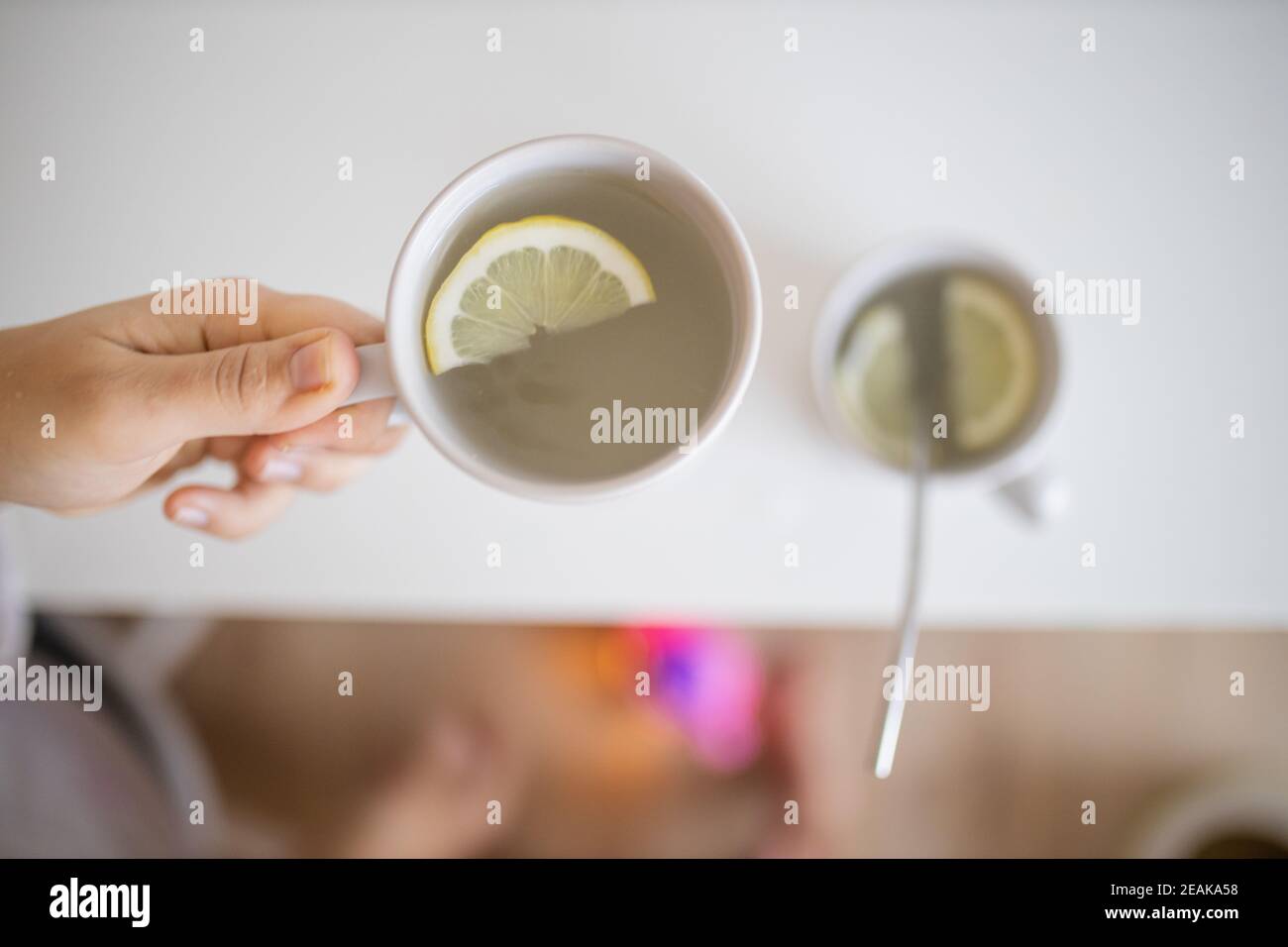 Hand holding a cup of lemon tea with a lemon slice inside Stock Photo ...