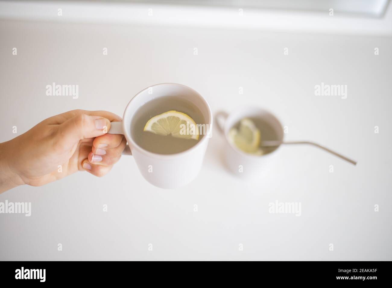 Hand holding a cup of lemon tea with a lemon slice inside Stock Photo ...