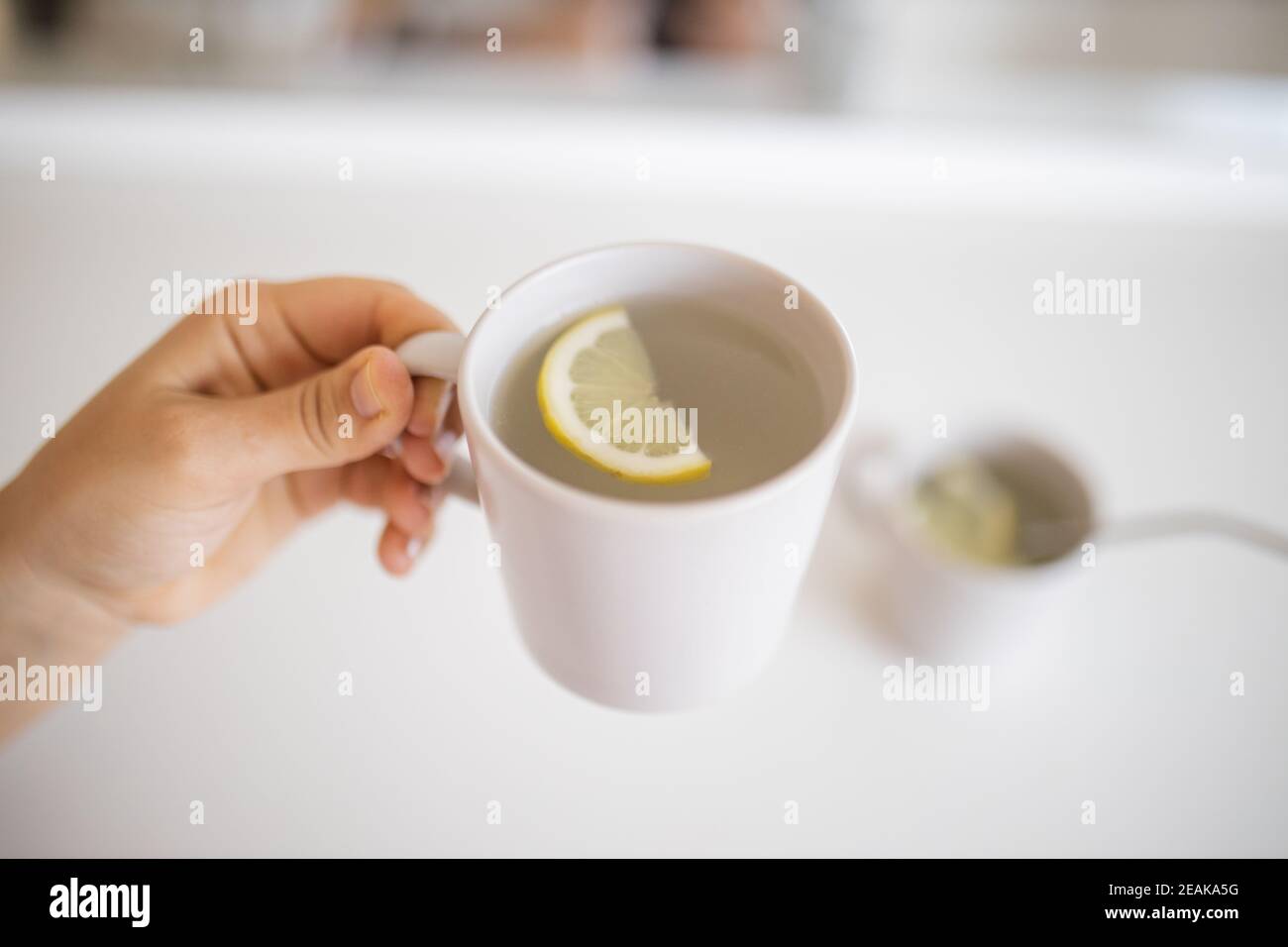 Hand holding a cup of lemon tea with a lemon slice inside Stock Photo ...
