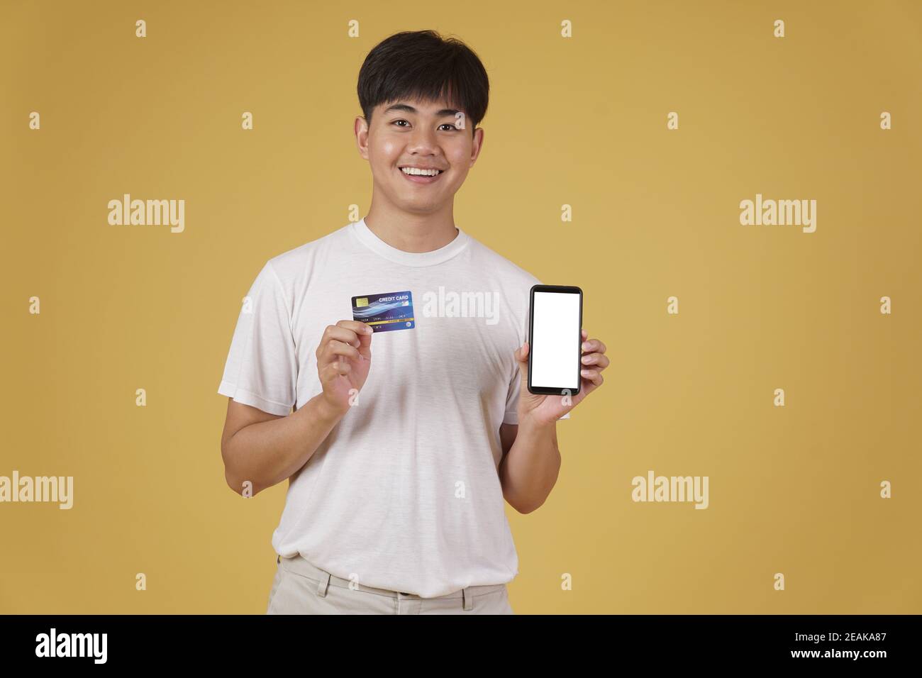 portrait of happy young asian man dressed casually holding smartphone ...