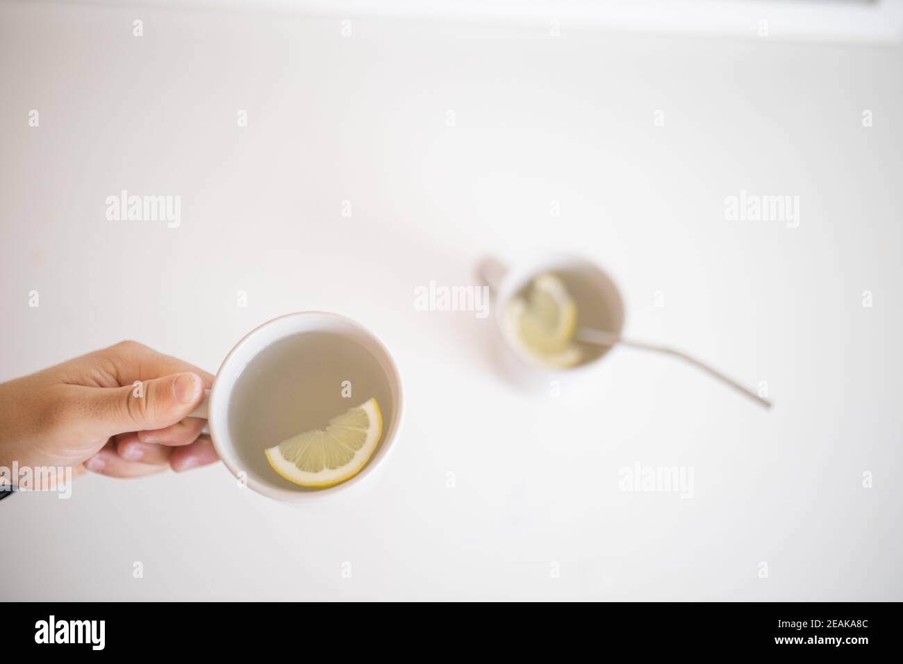 Hand holding a cup of lemon tea with a lemon slice inside Stock Photo ...