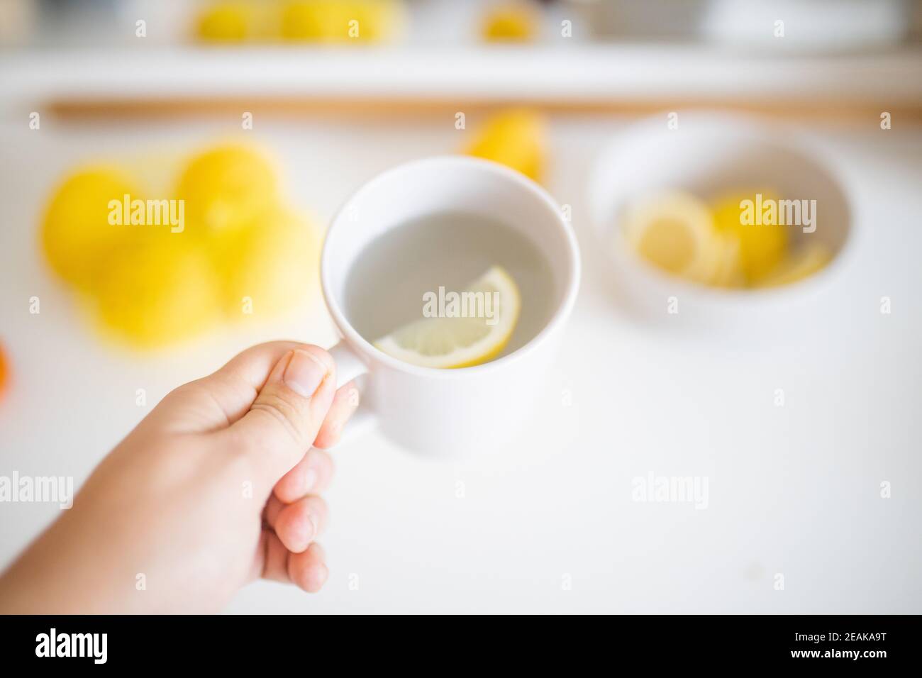 Hand holding a cup of lemon tea with a lemon slice inside Stock Photo ...