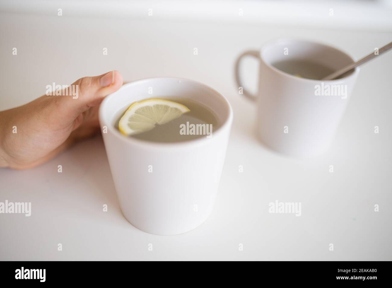 Hand holding a cup of lemon tea with a lemon slice inside Stock Photo ...