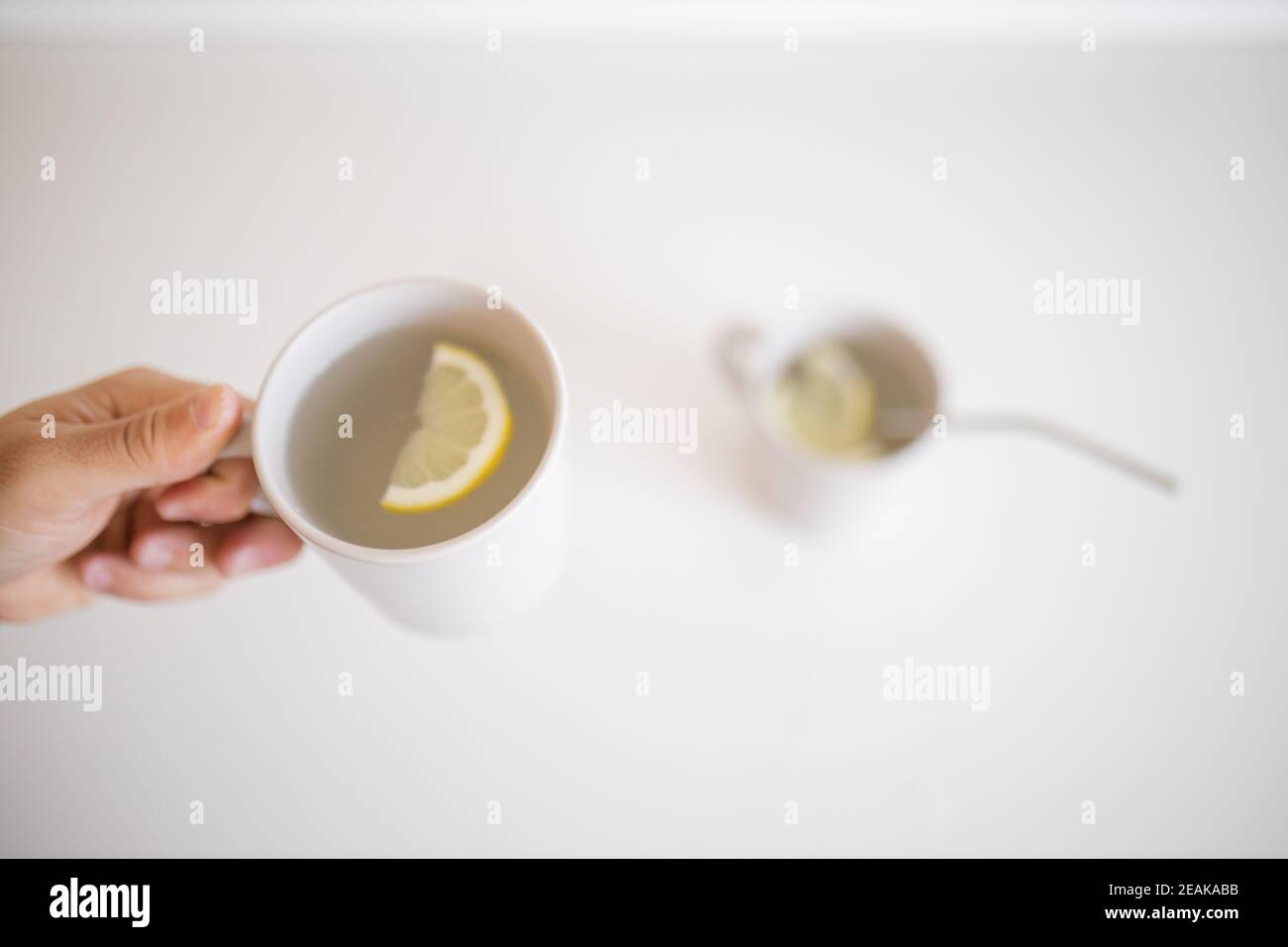 Hand holding a cup of lemon tea with a lemon slice inside Stock Photo ...