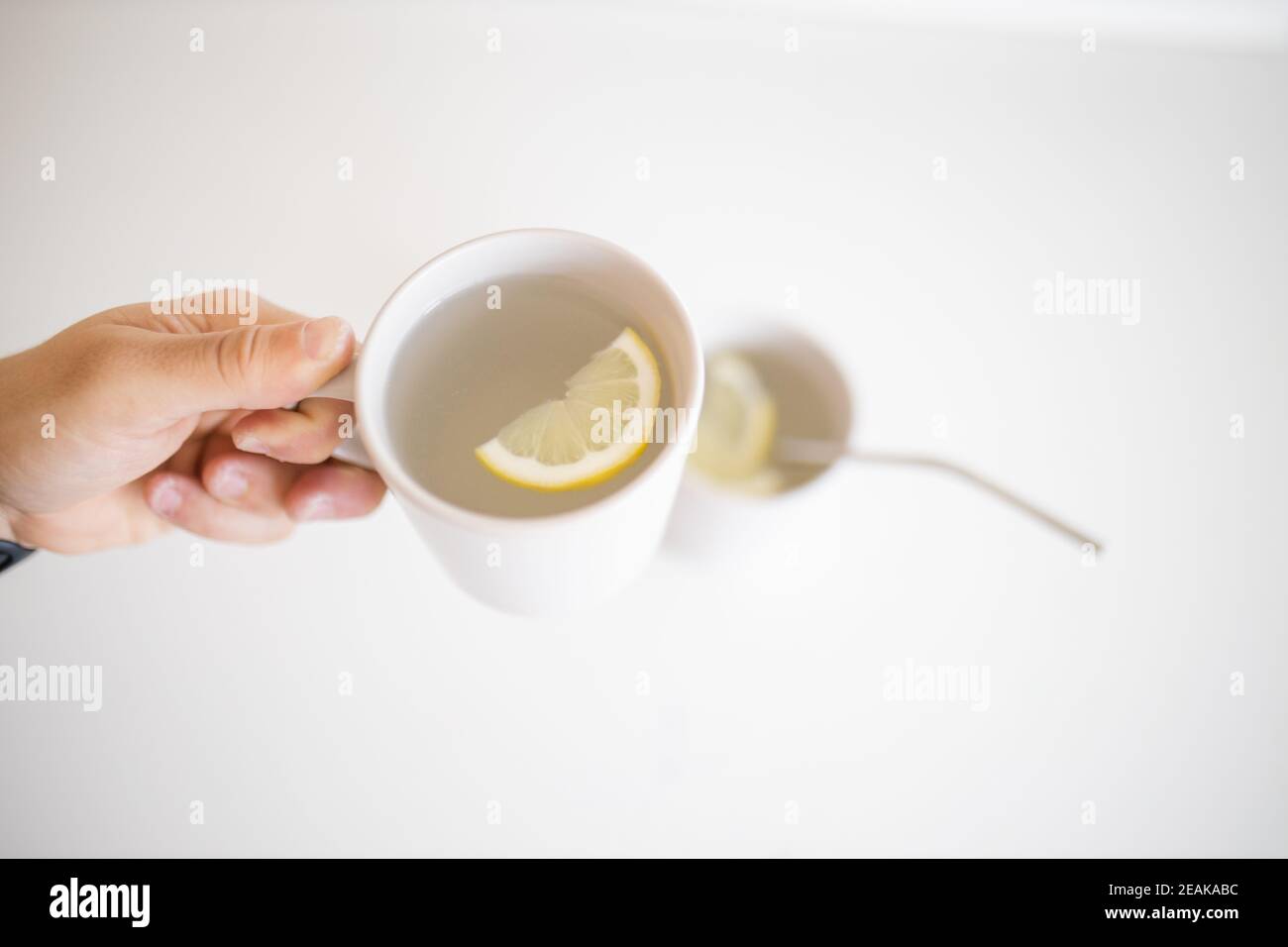 Hand holding a cup of lemon tea with a lemon slice inside Stock Photo ...