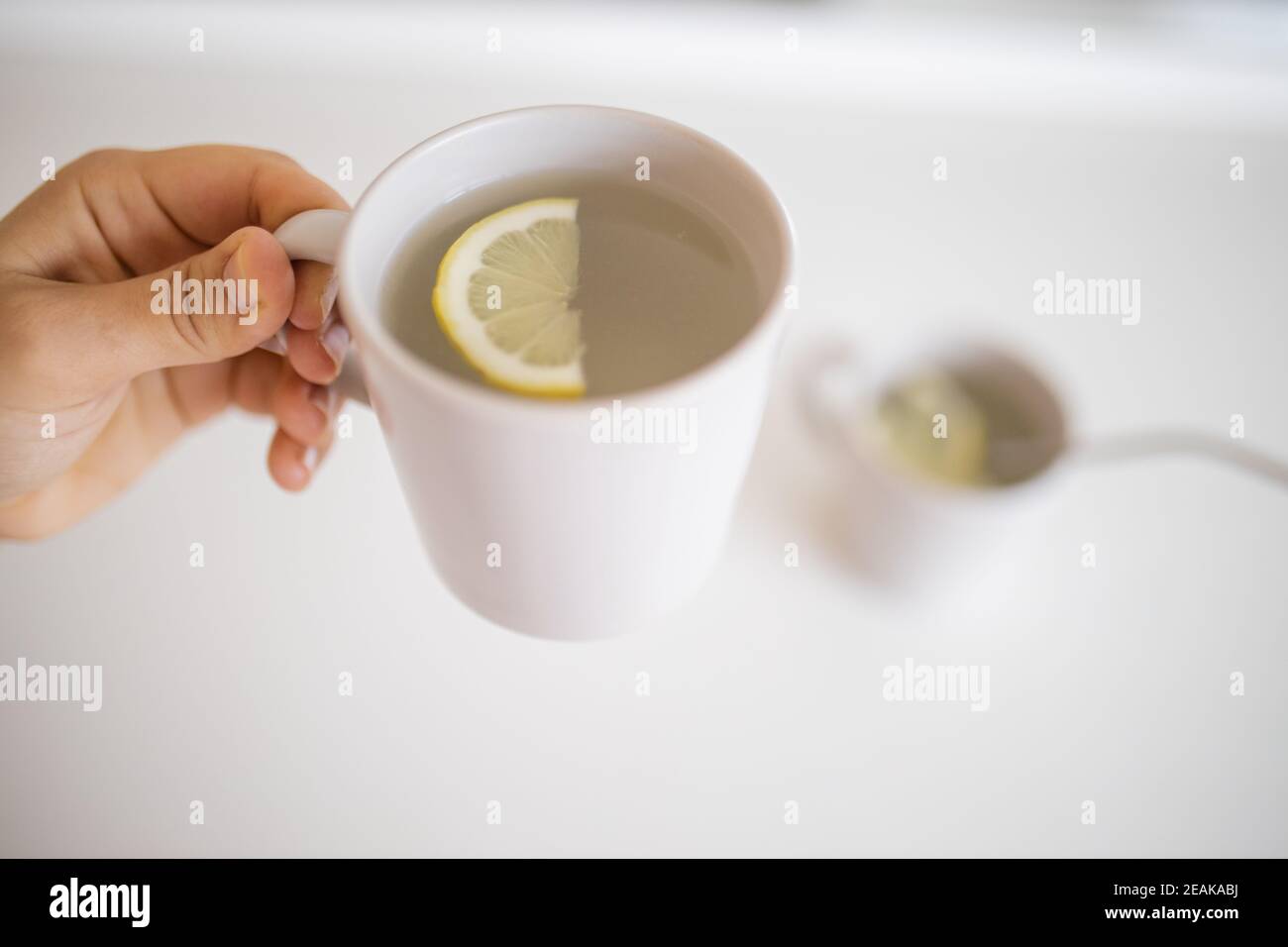 Hand holding a cup of lemon tea with a lemon slice inside Stock Photo ...