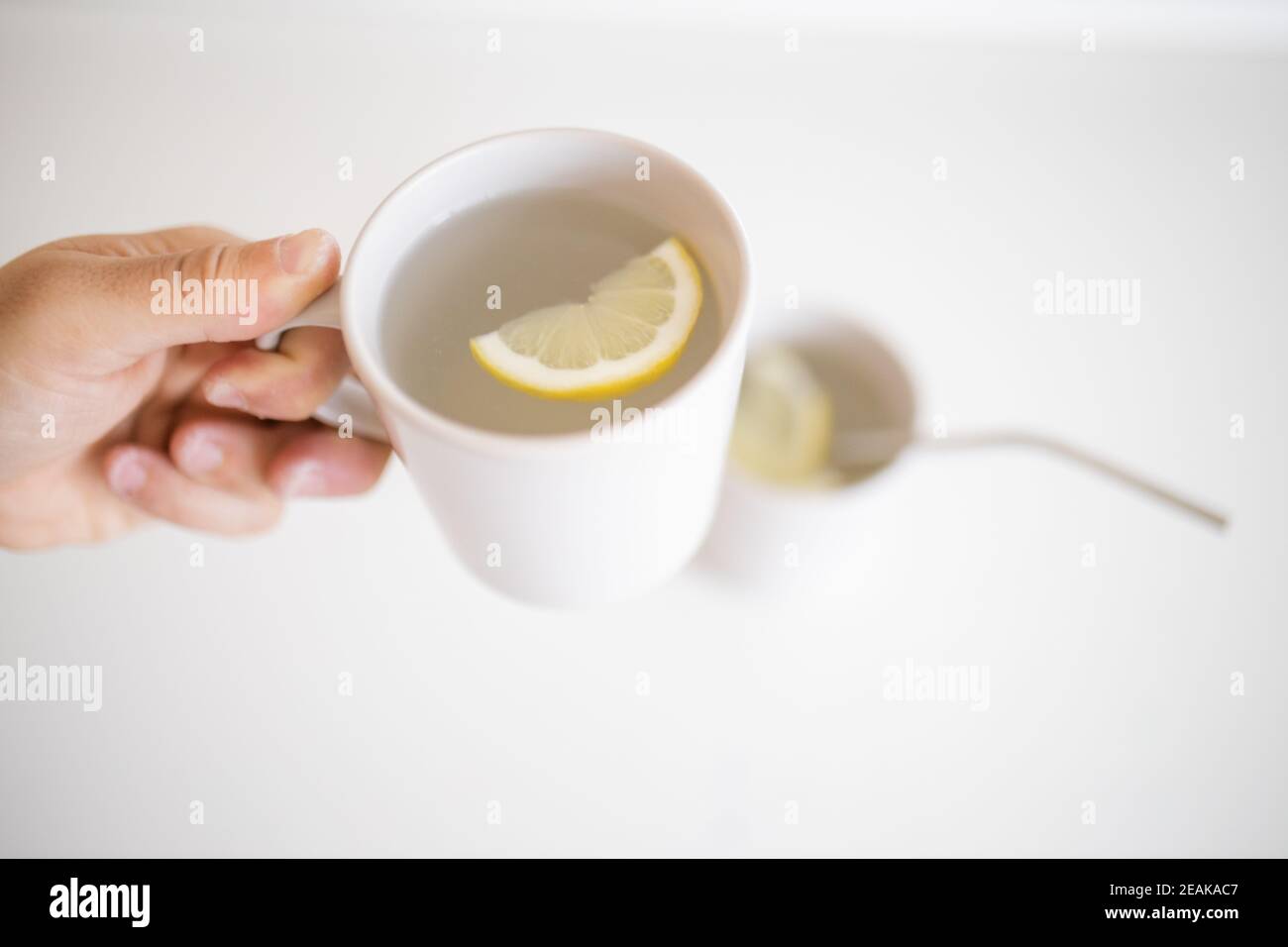 Hand holding a cup of lemon tea with a lemon slice inside Stock Photo ...
