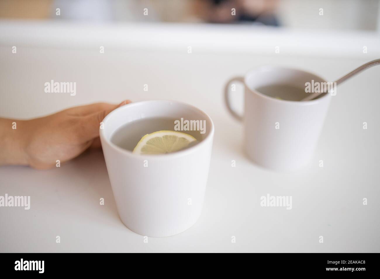 Hand holding a cup of lemon tea with a lemon slice inside Stock Photo ...