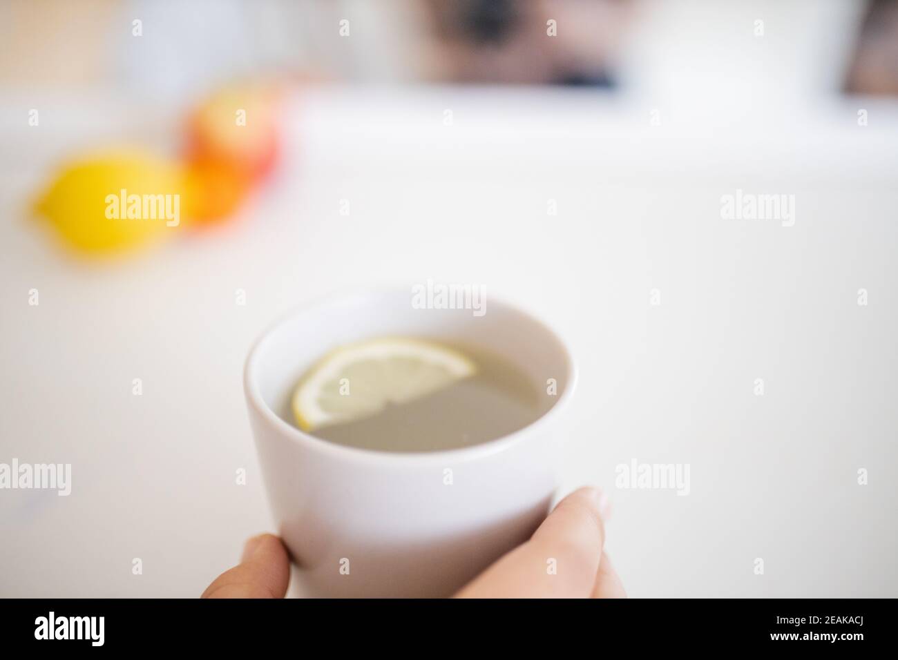 Hand holding a cup of lemon tea with a lemon slice inside Stock Photo ...
