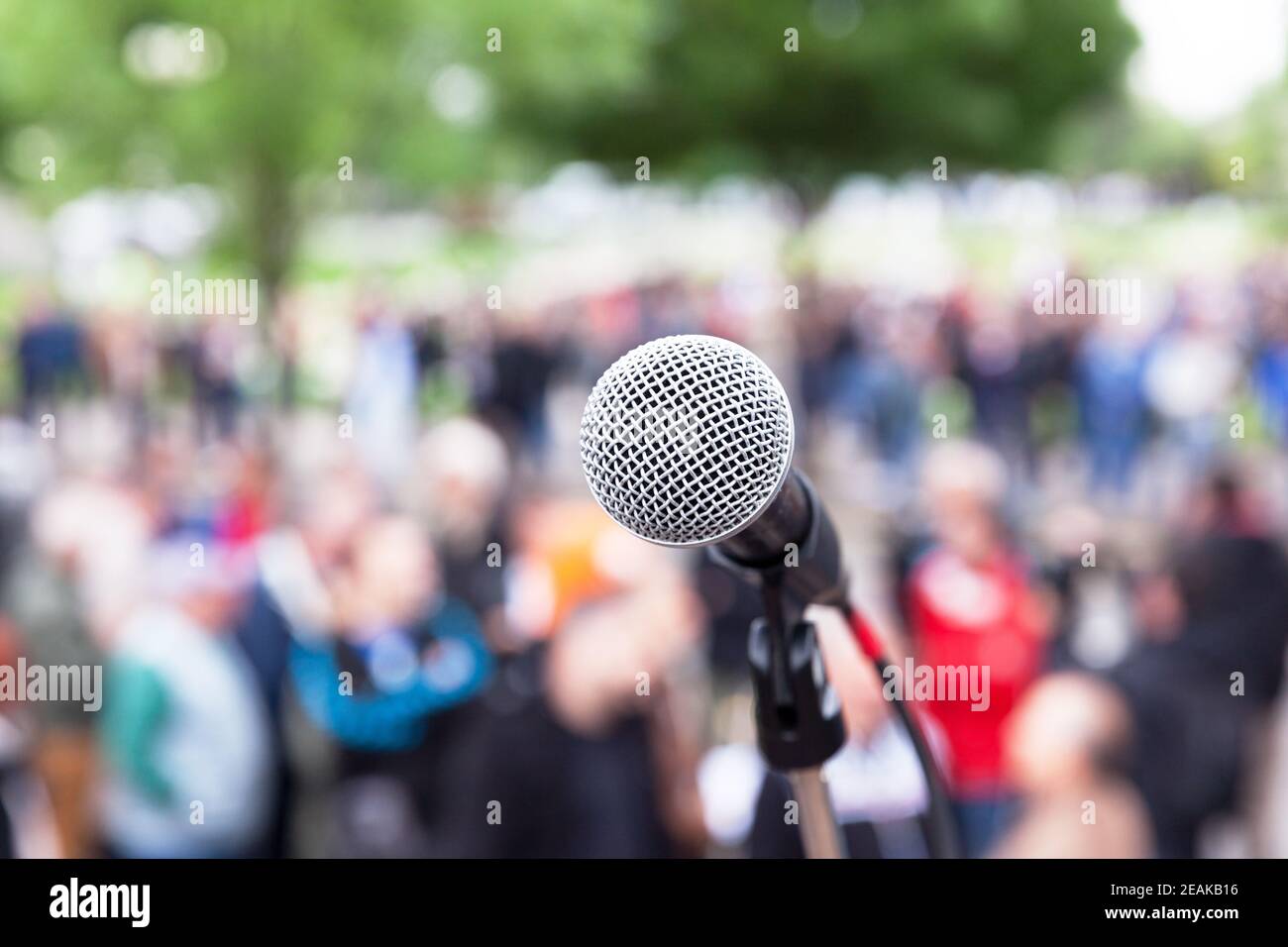 Microphone in focus, blurred people at street protest in background ...