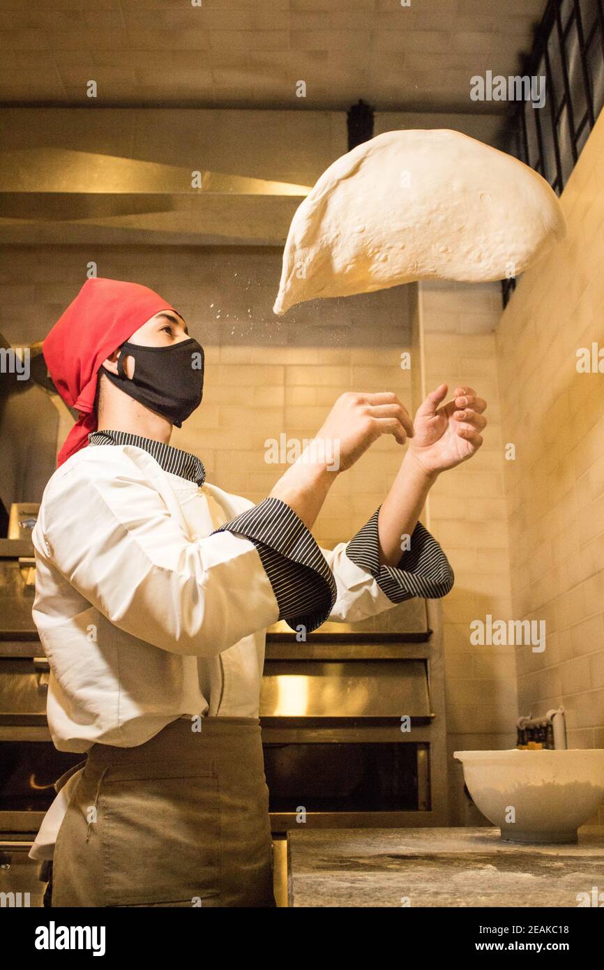 Vertical shot of dough flying through the air to become a disc in the ...