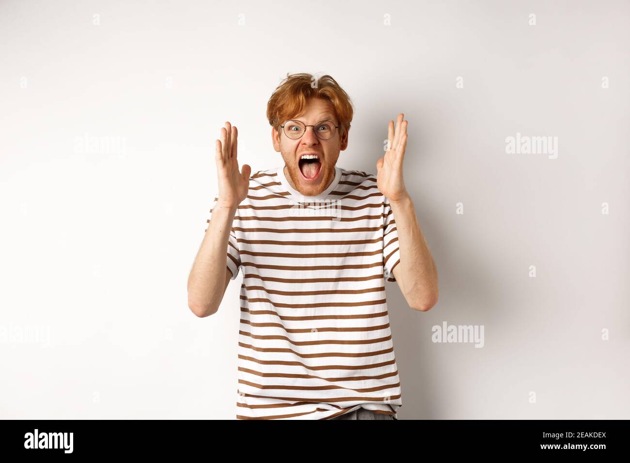 Angry young man with red hair shouting at camera, screaming and looking ...