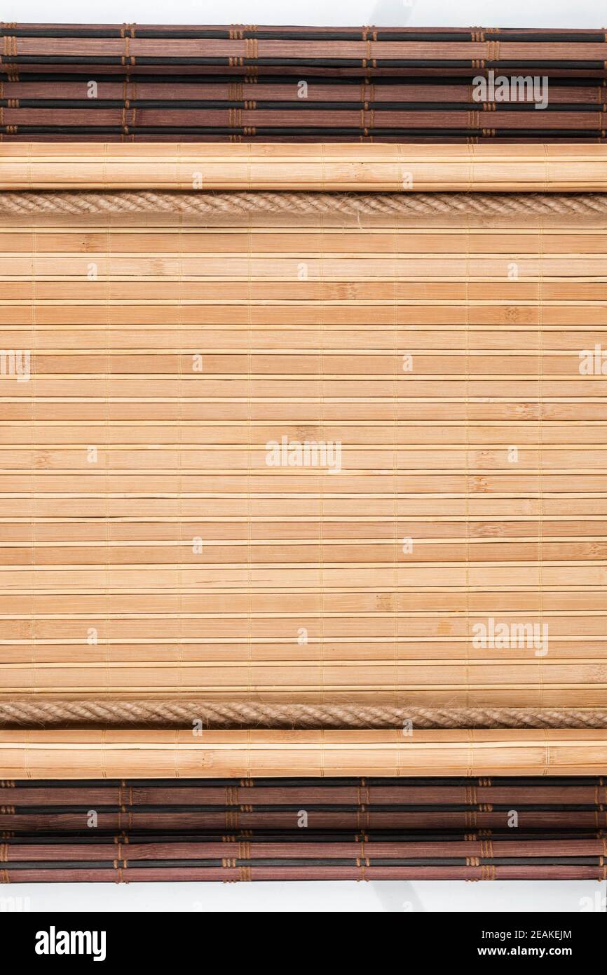 Bamboo mat with curled edges and rope, on white background. Space for ...