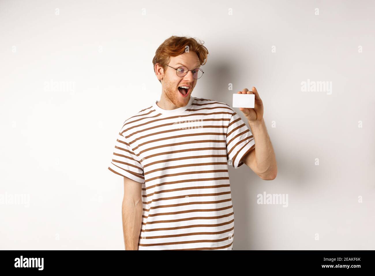 Shopping and finance concept. Excited young man with red hair, staring ...