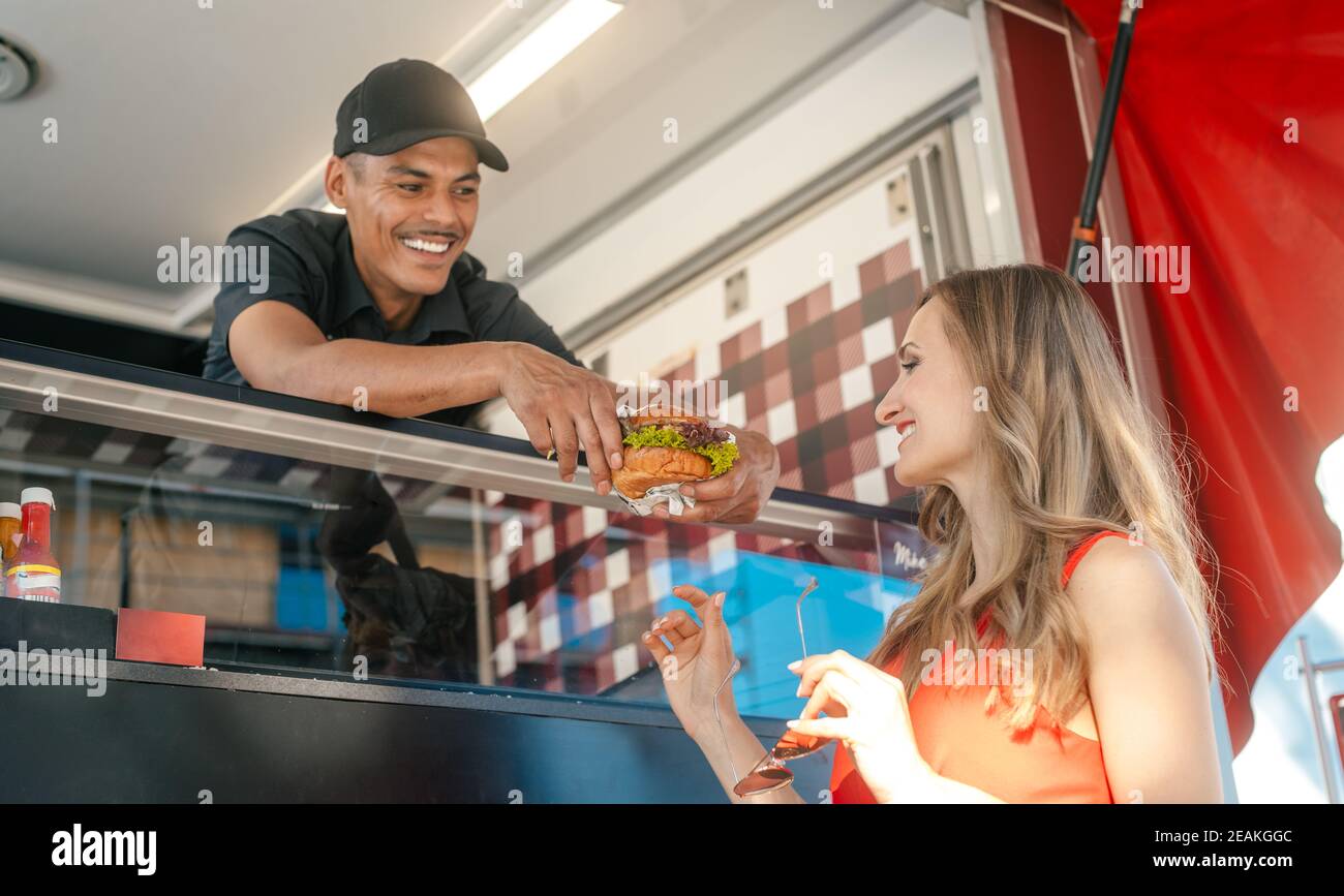 Cook in a food truck handing tasty burger over to woman customer Stock ...