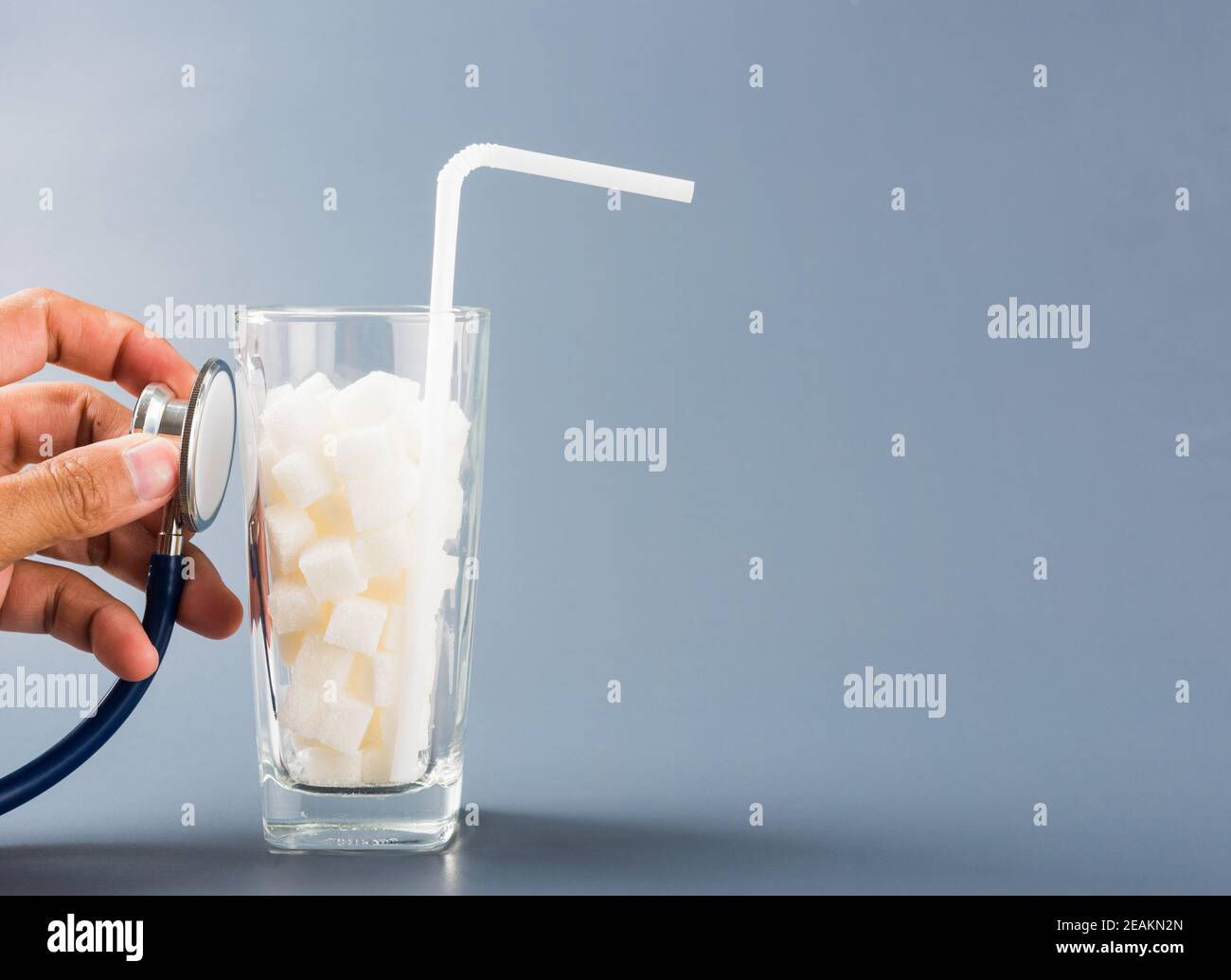 Hand of doctor hold stethoscope check on glass full of white sugar cube ...