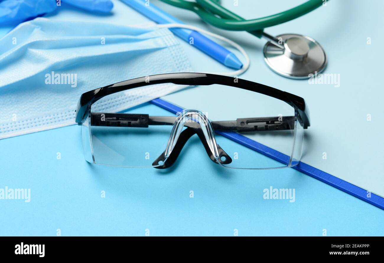 protective plastic glasses and disposable masks on a blue background ...