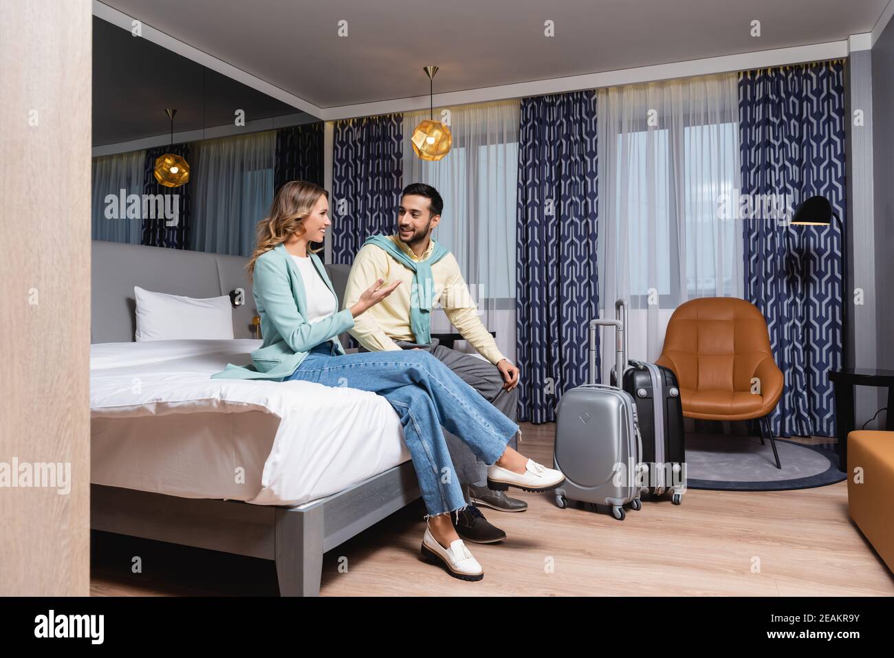 Smiling woman pointing with hand near suitcases and muslim boyfriend on ...