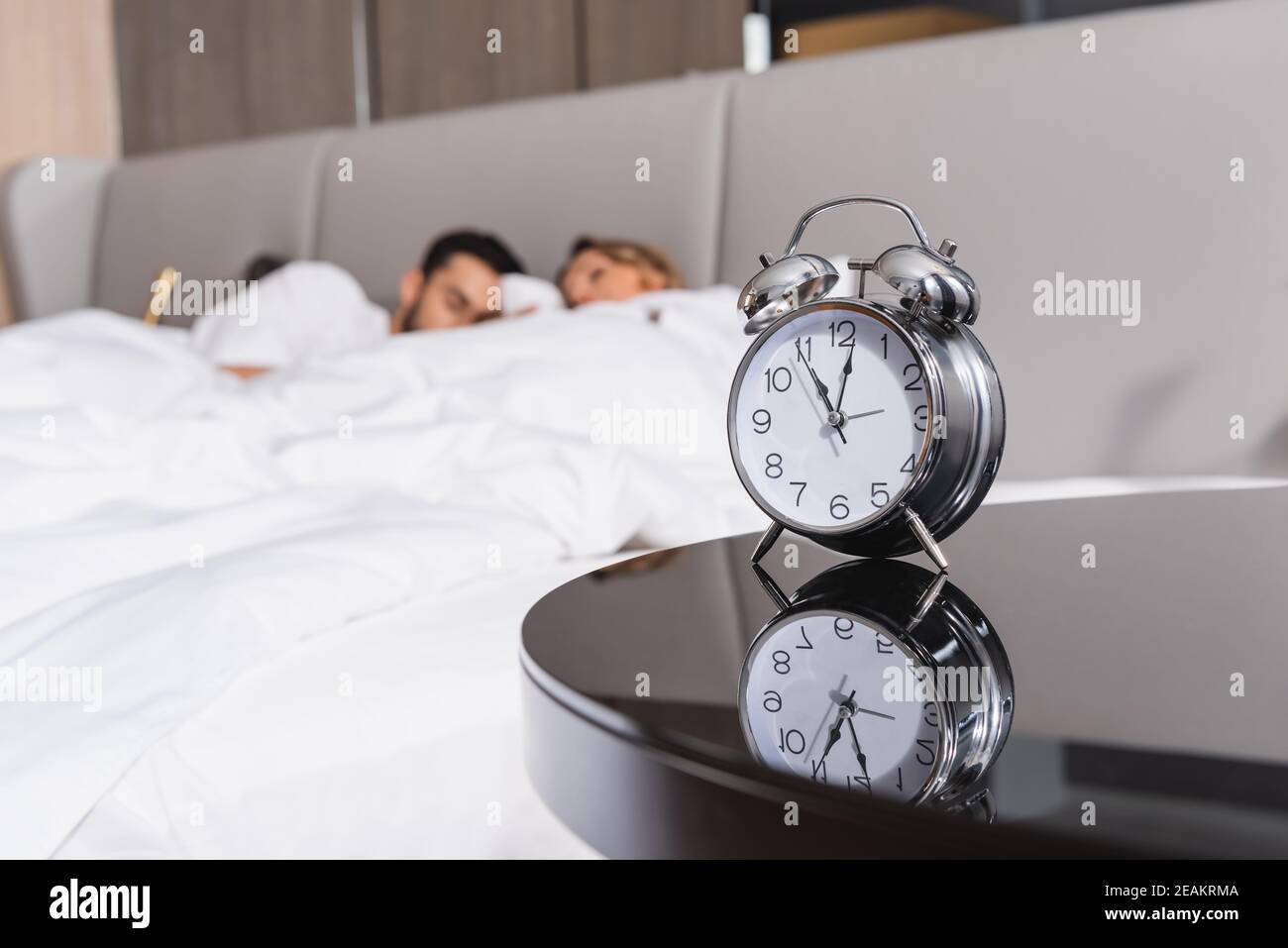 Alarm clock near sleeping couple on blurred background in hotel Stock ...