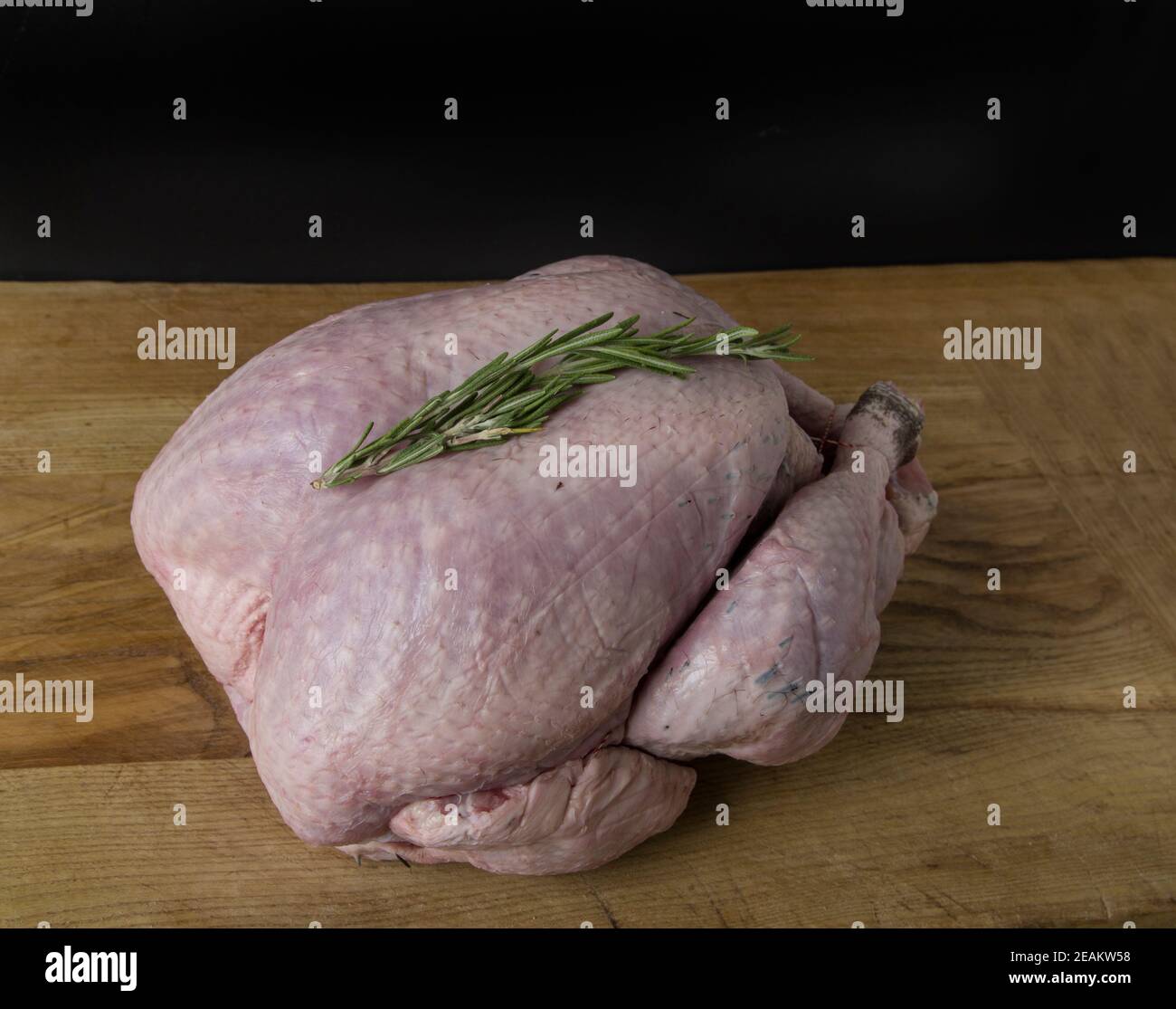 trussed raw turkey photographed on a wooden cutting board with a black ...