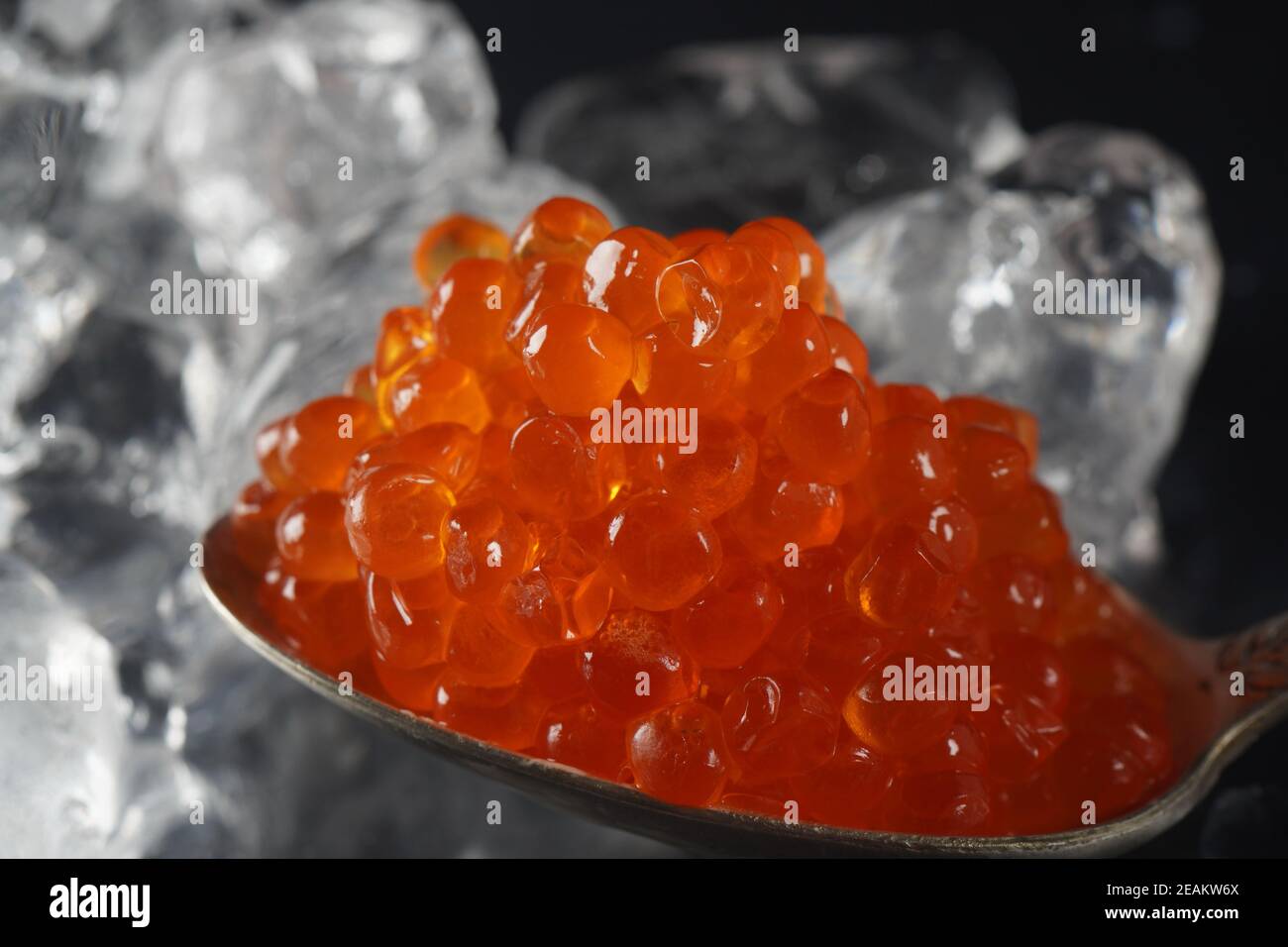 Red Caviar in a spoon on ice background. Close-up salmon caviar ...