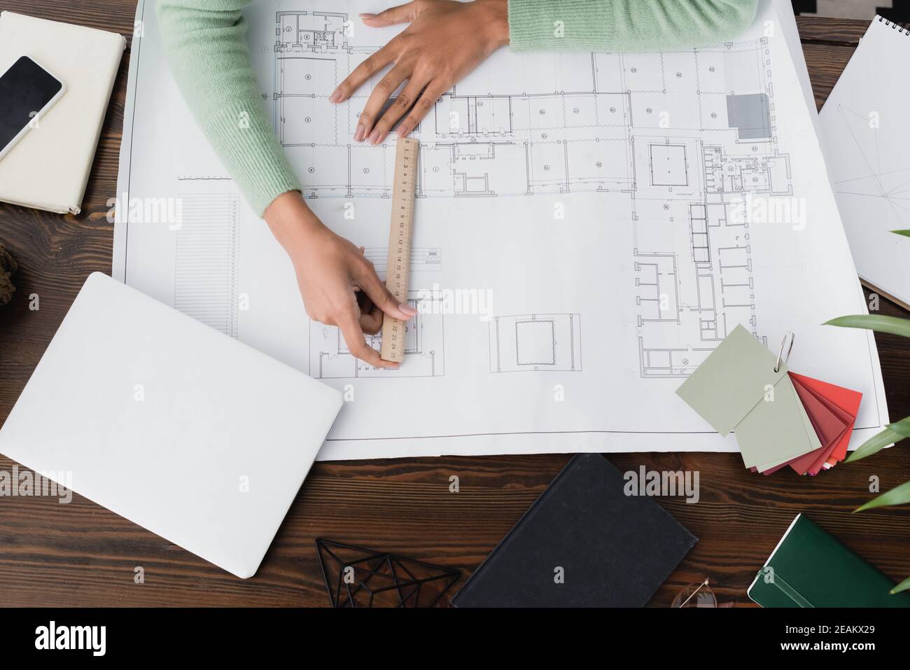top view of african american architect measuring blueprint with ruler ...