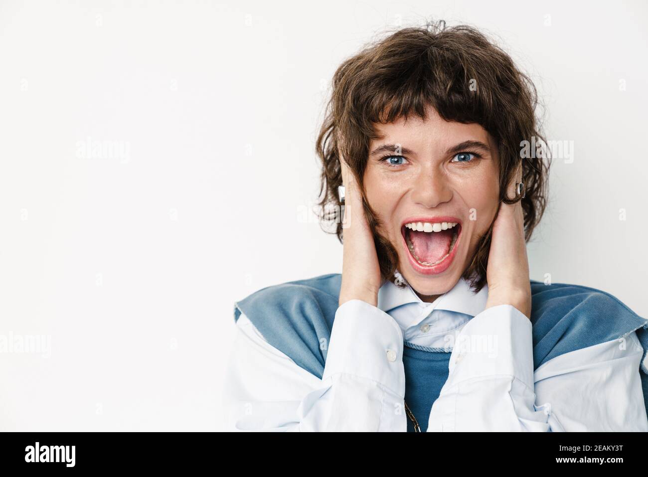 Excited beautiful girl screaming and covering her ears isolated over ...
