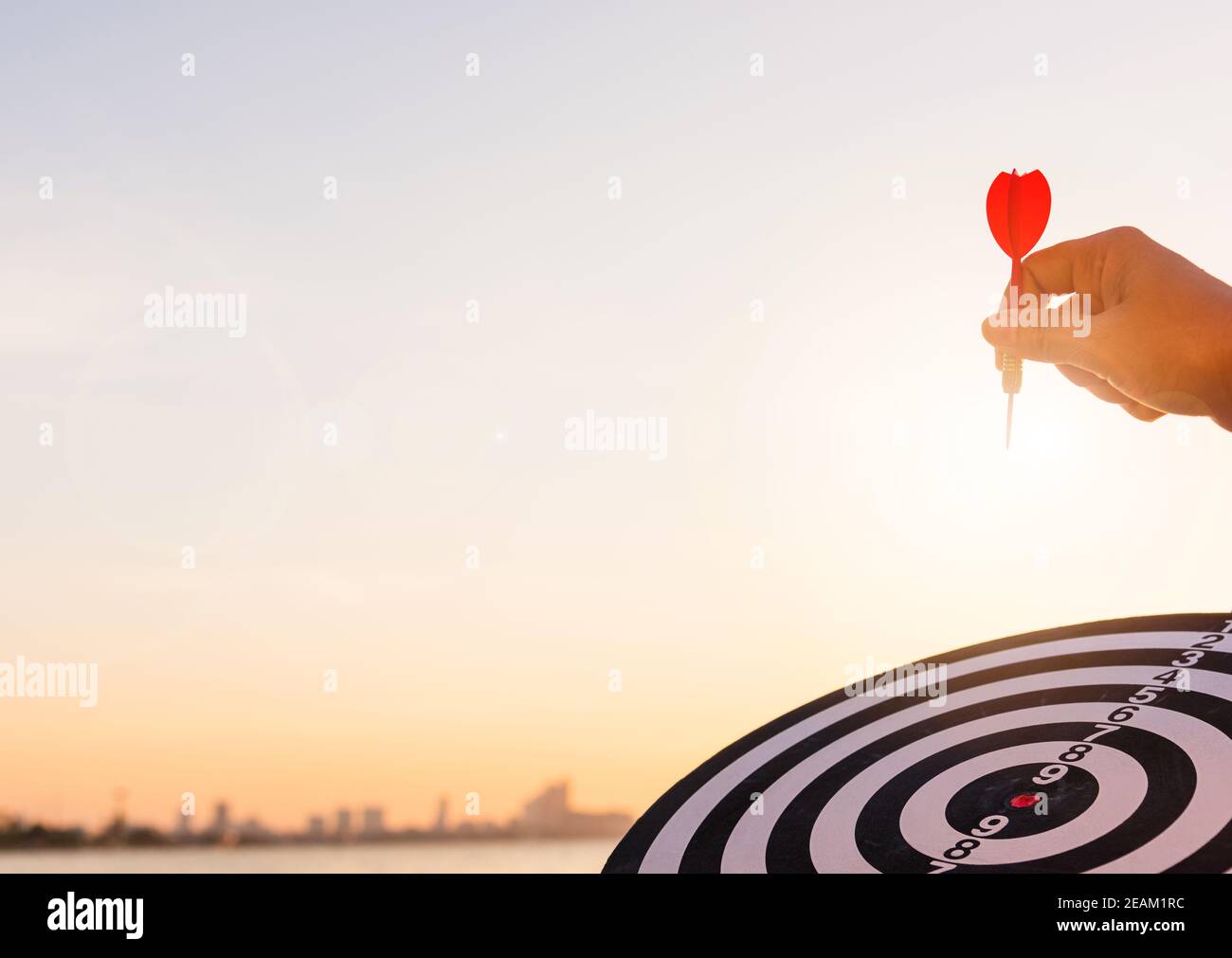 Hand hold of dart arrow on bullseye Stock Photo - Alamy