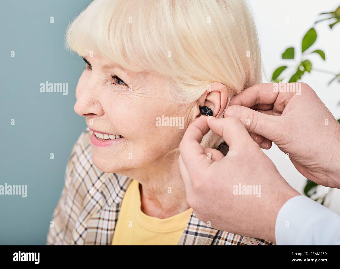 Audiologist inserting Intra-ear hearing aid to senior woman patient ...