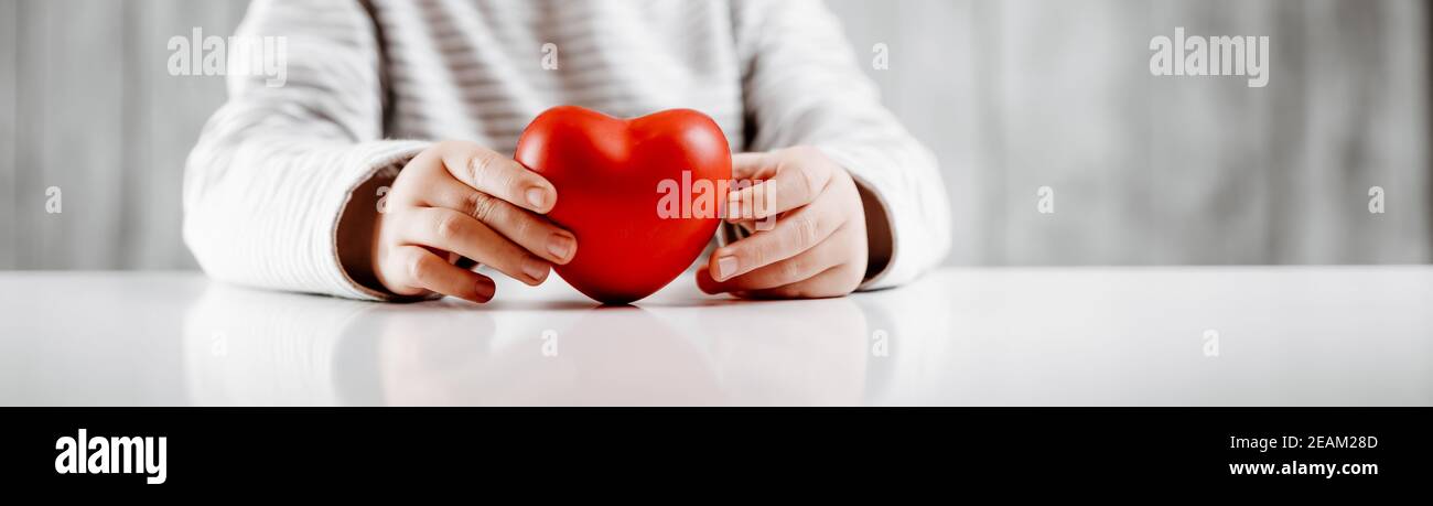 Cute little child holding red heart in hands Stock Photo - Alamy