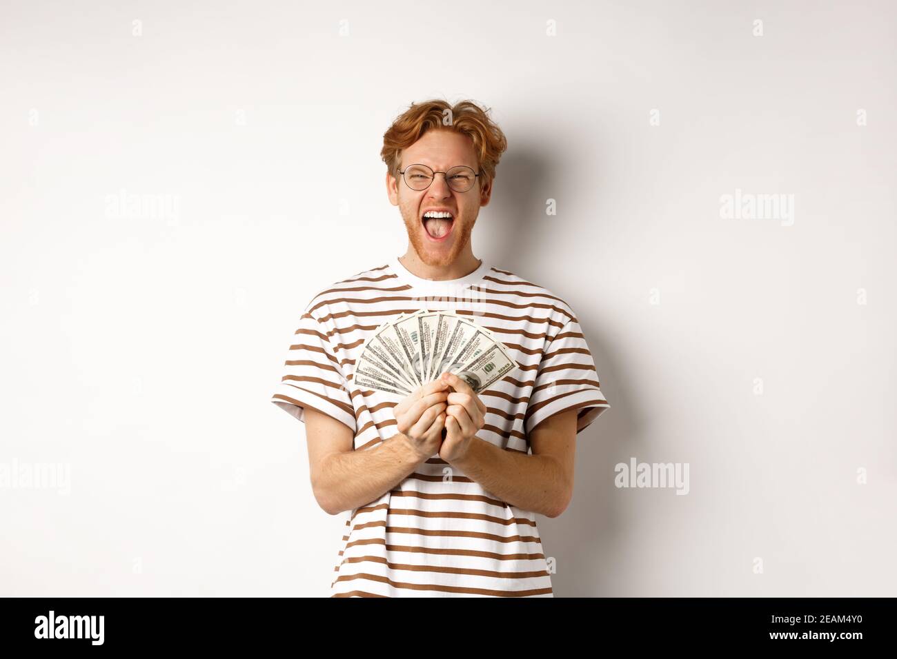Lucky young man with red hair showing dollars, winning money and ...