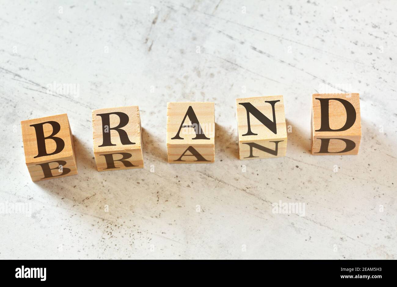 Five wooden cubes with word BRAND on white stone like board, view from ...