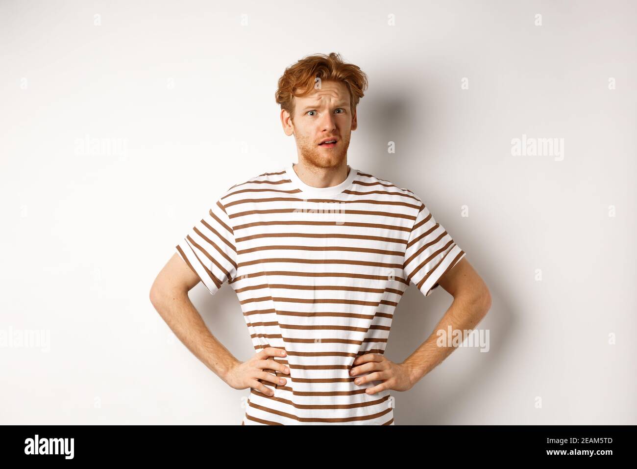 Confused and offended man with ginger curly hair staring at camera ...