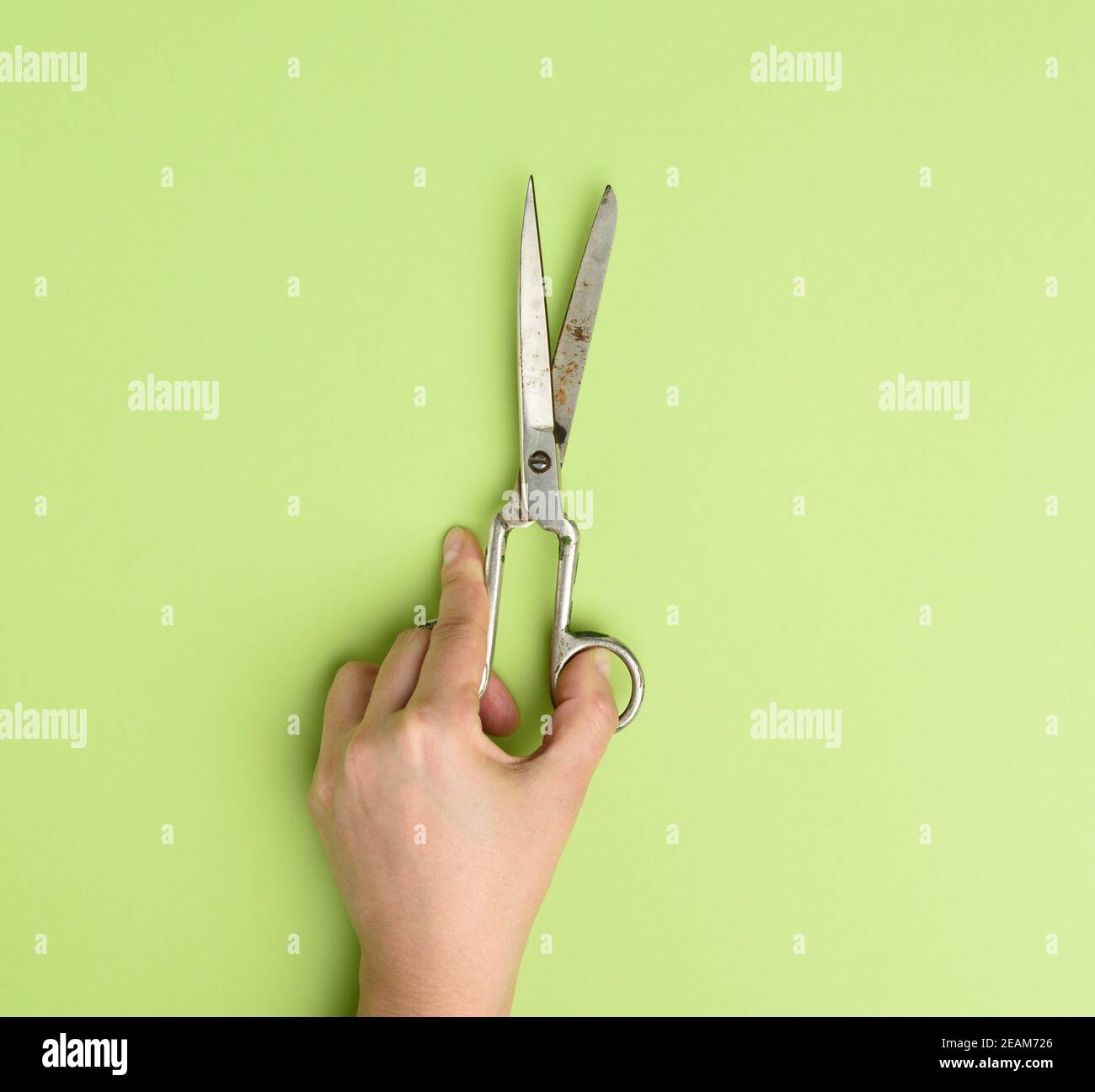 hand holds metal scissors on green background Stock Photo - Alamy