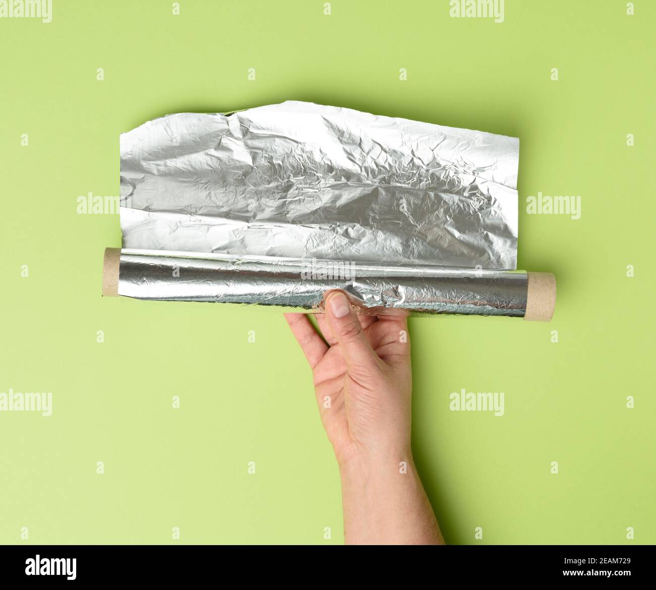 two female hands holds crumpled silver foil on a green background Stock ...