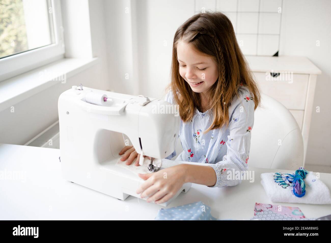 Smiling Little Girl At The Table With Sewing Machine Stock Photo - Alamy