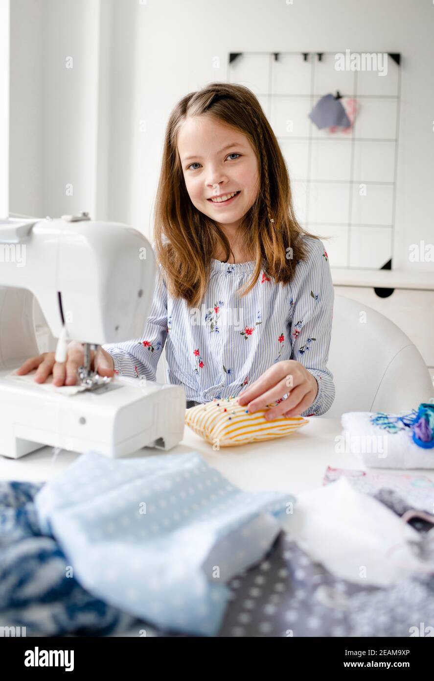 Smiling Little Girl At The Table With Sewing Machine Stock Photo - Alamy