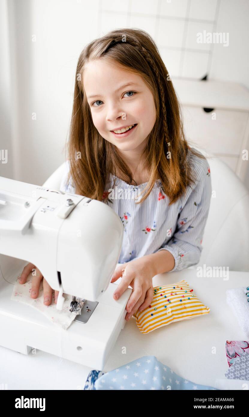 Smiling Little Girl At The Table With Sewing Machine Stock Photo - Alamy