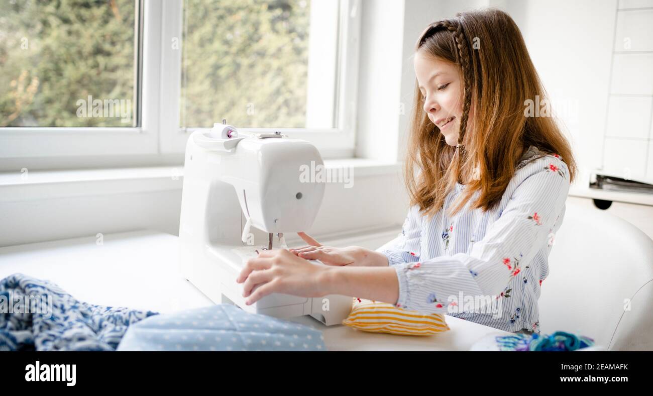 Smiling Little Girl At The Table With Sewing Machine Stock Photo - Alamy