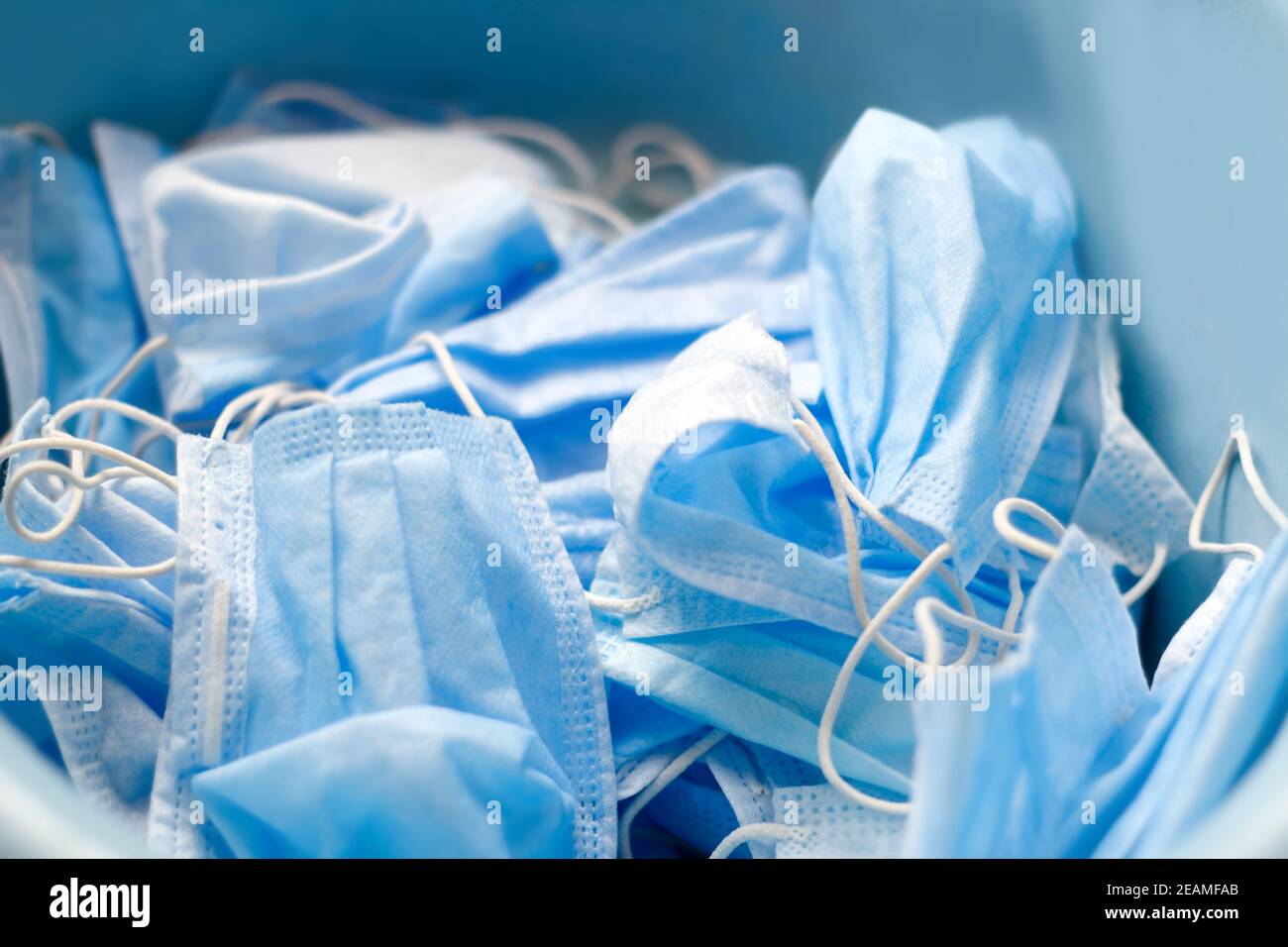 Many stacked medical blue masks. A lot of used crumpled protective ...