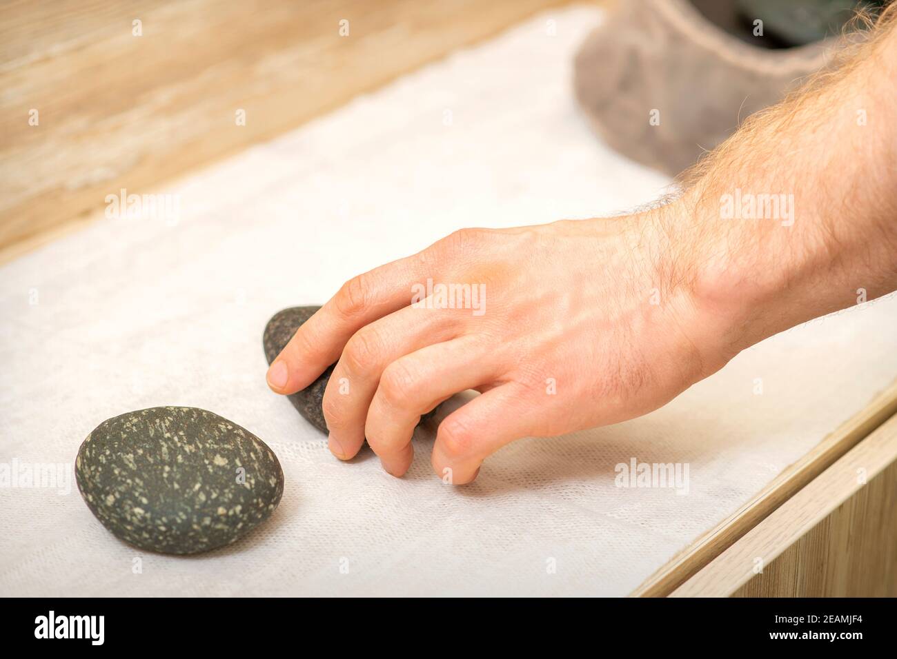 Hand of massage therapist taking massage stones from the table before ...