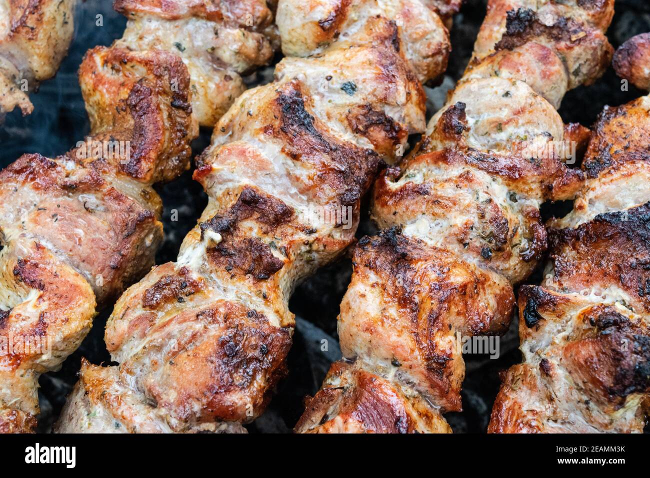 Frying pork on a skewer over a brazier. Turning meat over coals ...